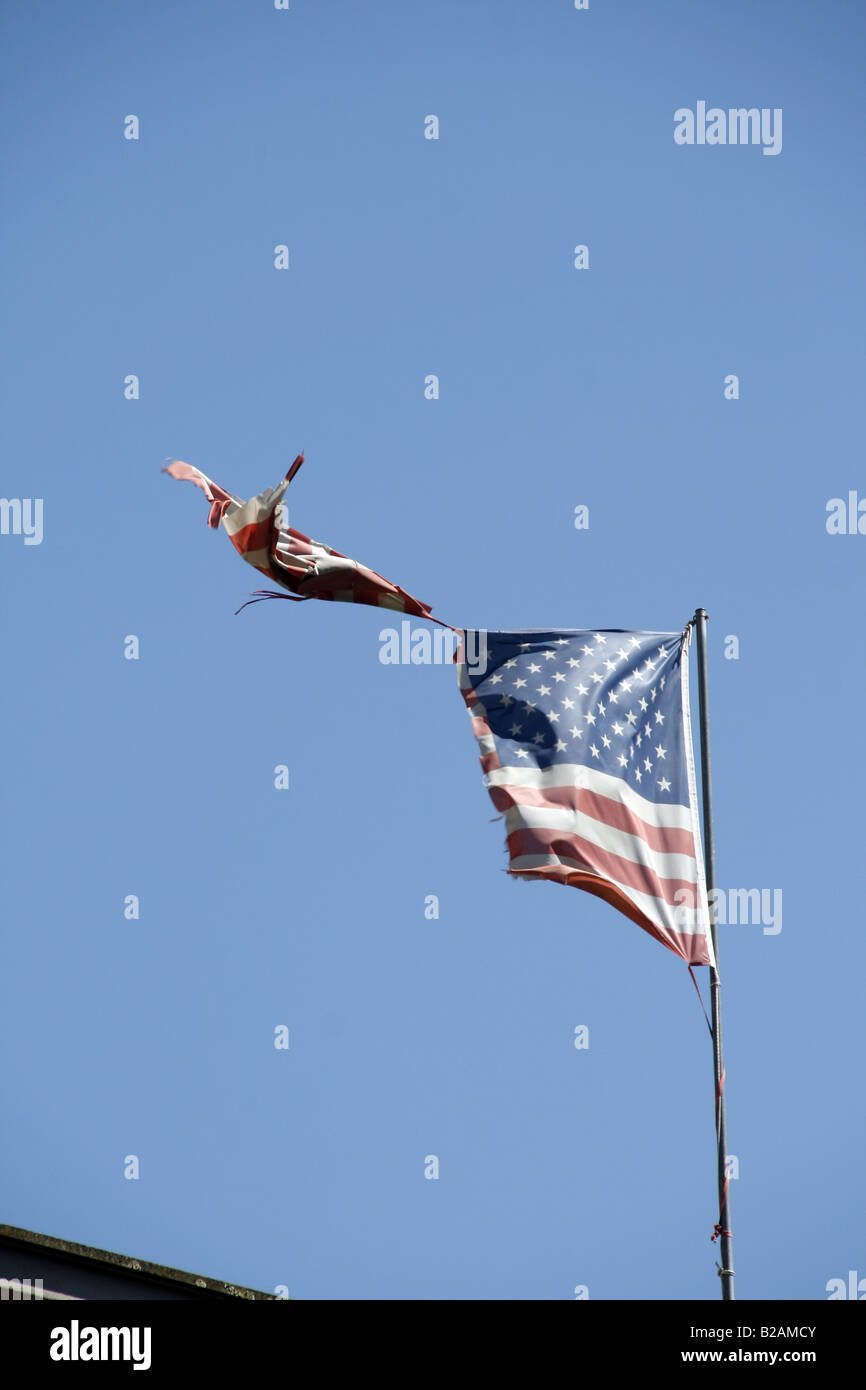 one damaged american flag flying in blue sky Stock Photo - Alamy