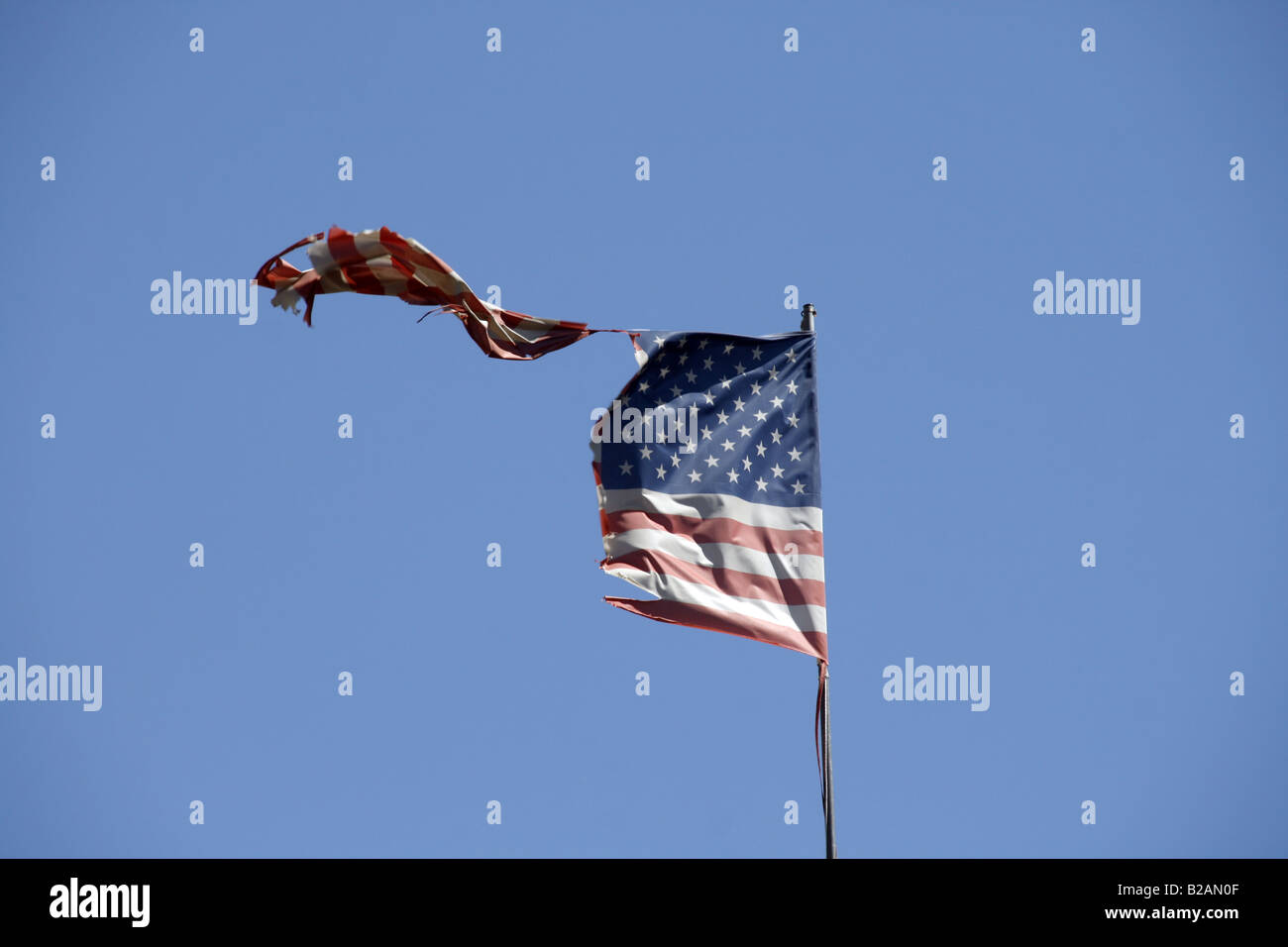 one damaged american flag flying in blue sky Stock Photo - Alamy