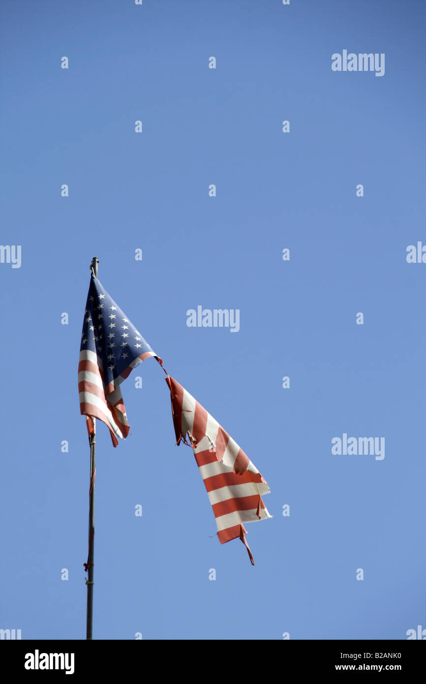 one damaged american flag flying in blue sky Stock Photo - Alamy