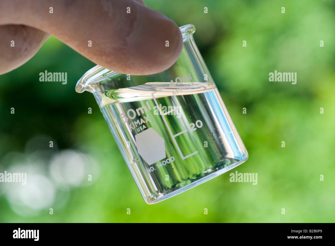 hand holding small beaker of clear fluid outdoors Stock Photo - Alamy