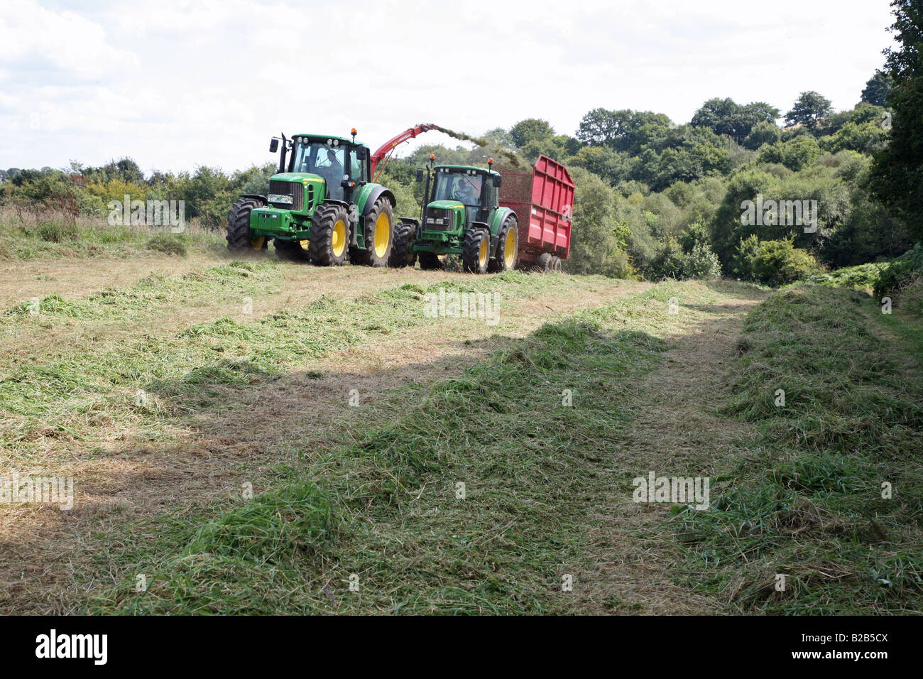 Two tractors and a trailer collecting grass for silage Stock Photo - Alamy