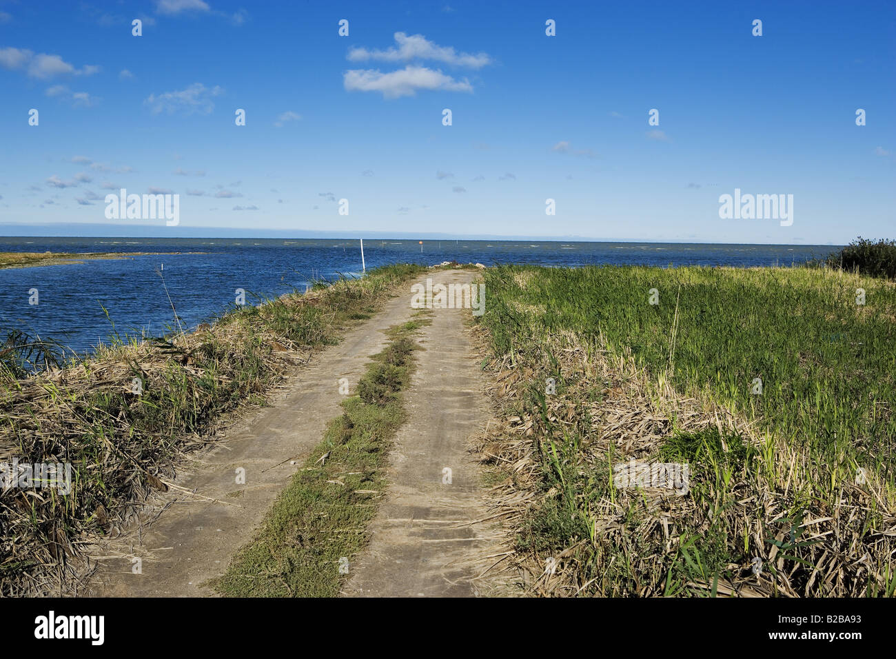 Dirt track road by body of water Stock Photo - Alamy