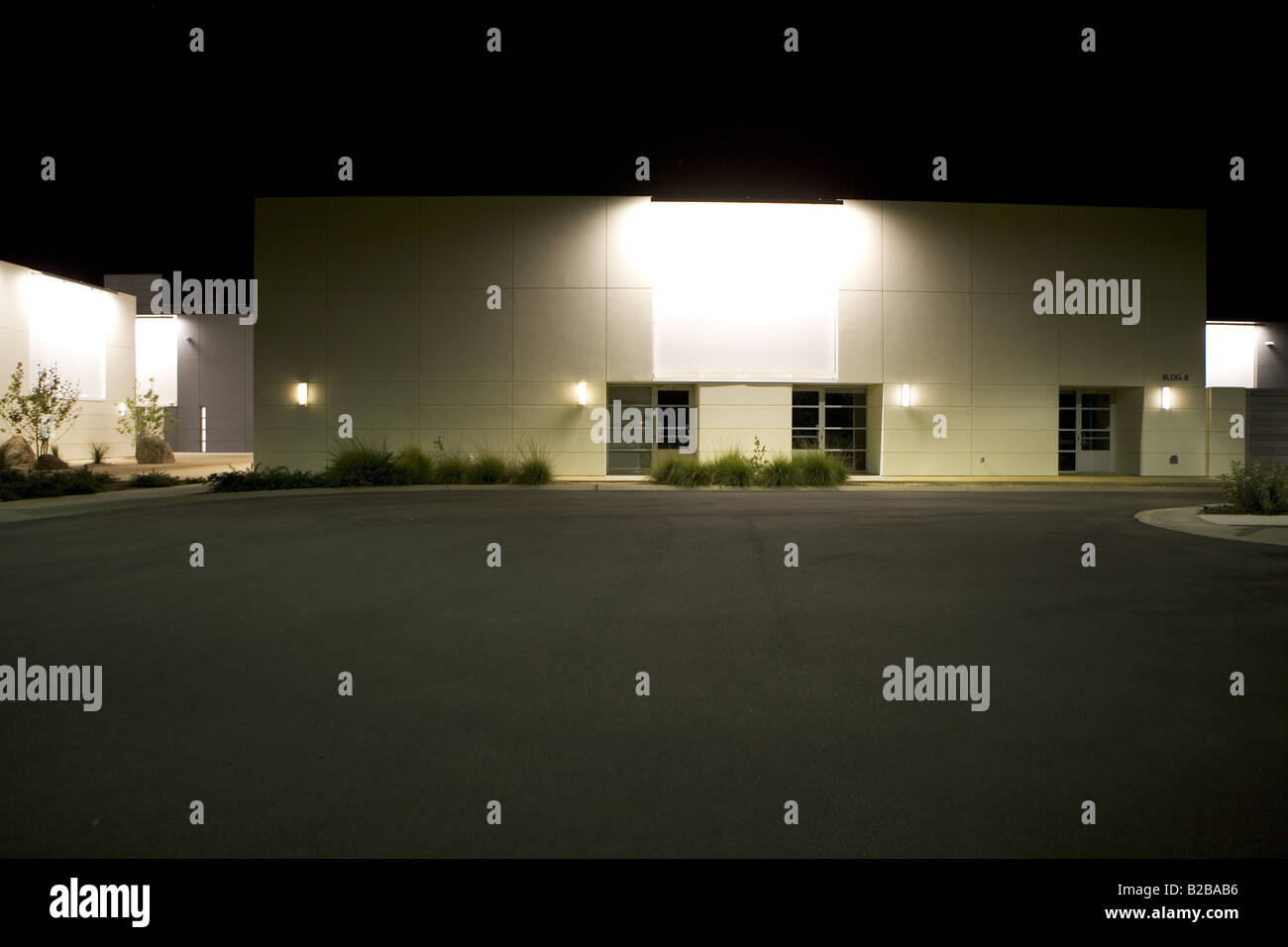 Building with empty parking lot at night Stock Photo - Alamy