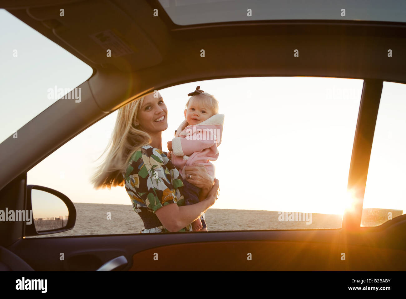 Young woman holding baby viewed through window of Toyota Forerunner ...