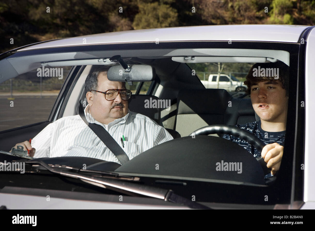 Driving instructor with teen taking driving test Stock Photo - Alamy