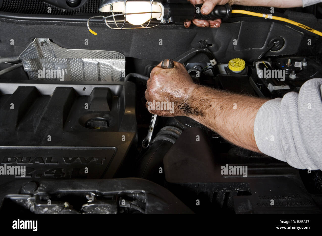 Auto mechanic with wrench and work light works on engine Stock Photo ...