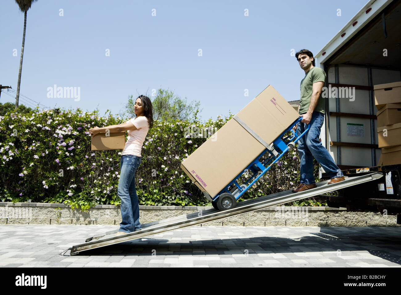 Young couple moving boxes out of moving truck Stock Photo - Alamy
