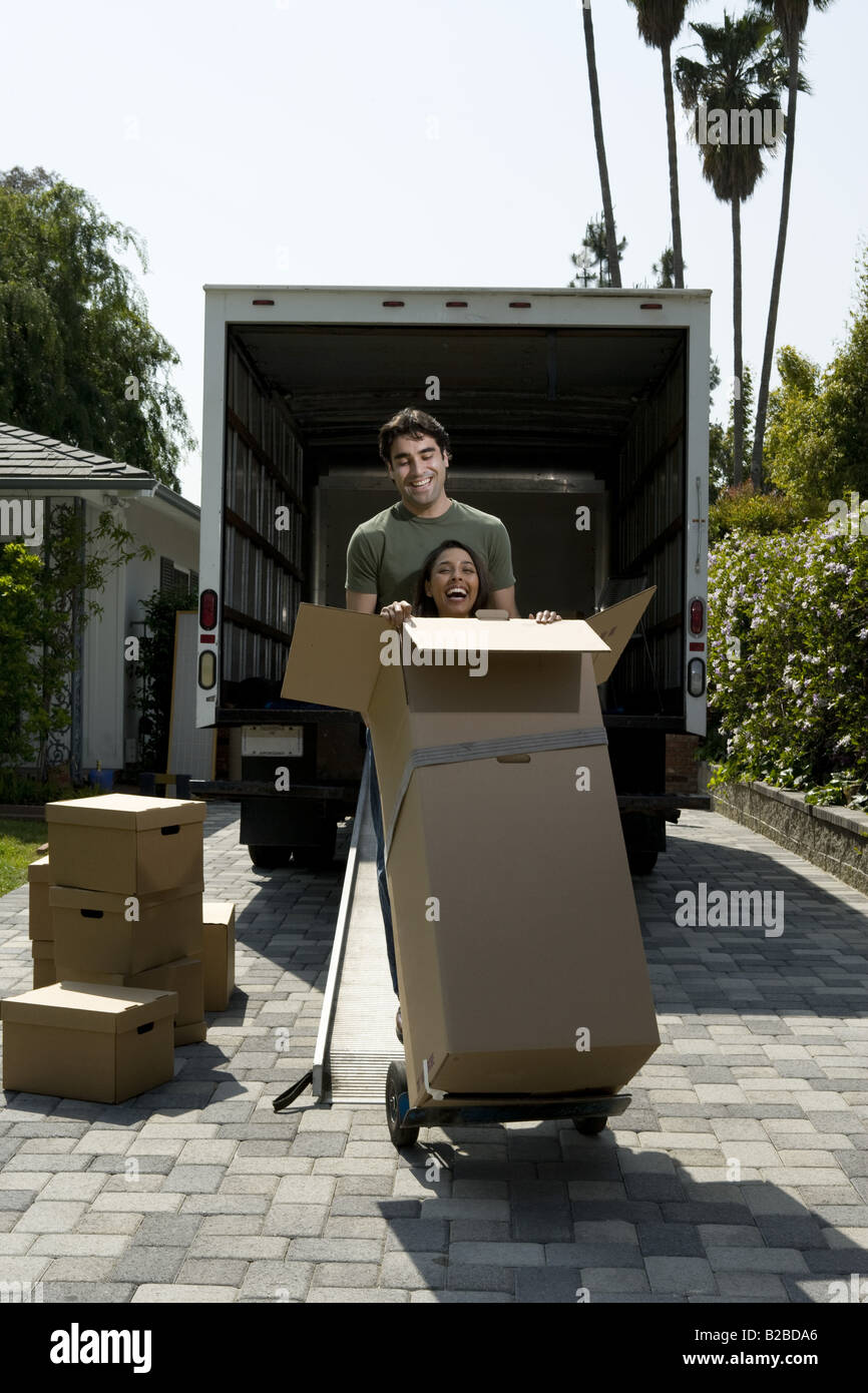 Young man pushing young woman on dolly down moving truck ramp Stock ...