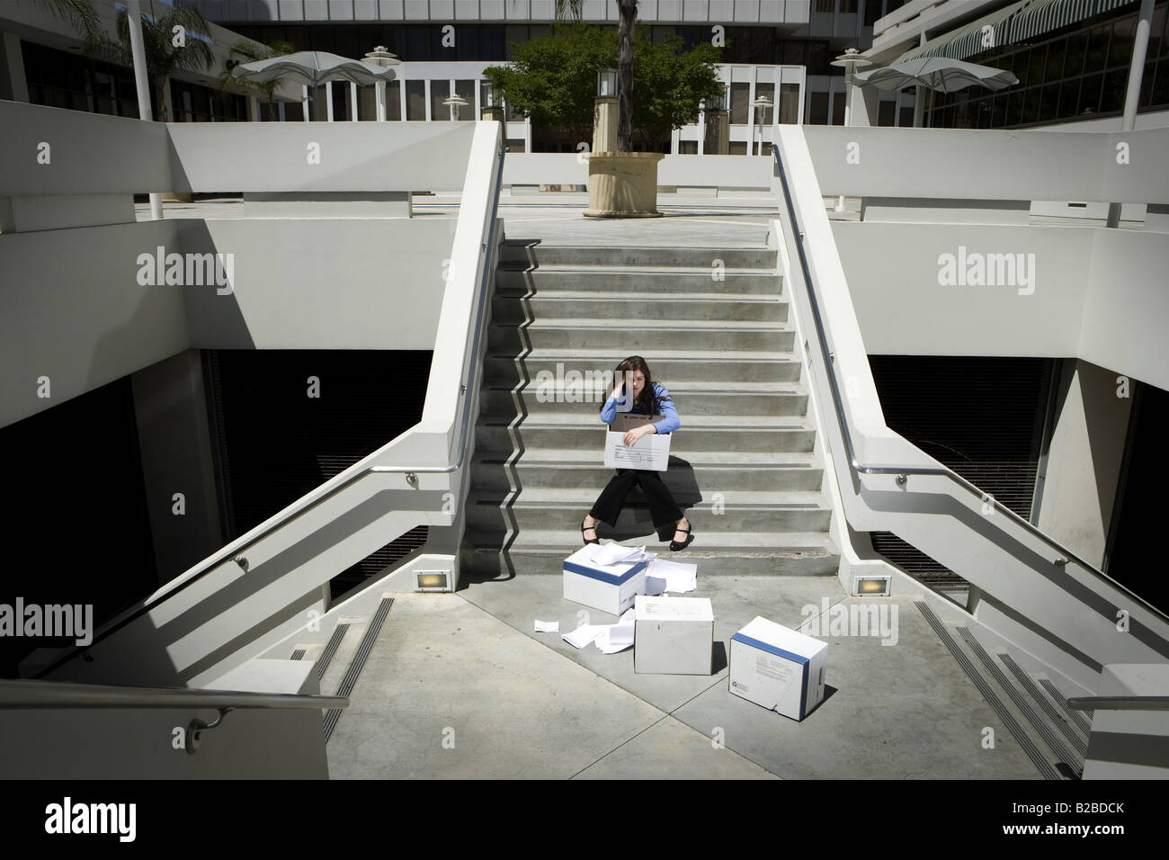 Businesswoman sitting on steps by dropped boxes of paperwork Stock ...