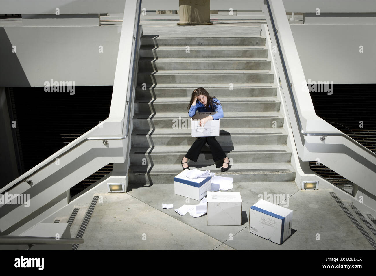 Businesswoman sitting on steps by dropped boxes of paperwork Stock ...
