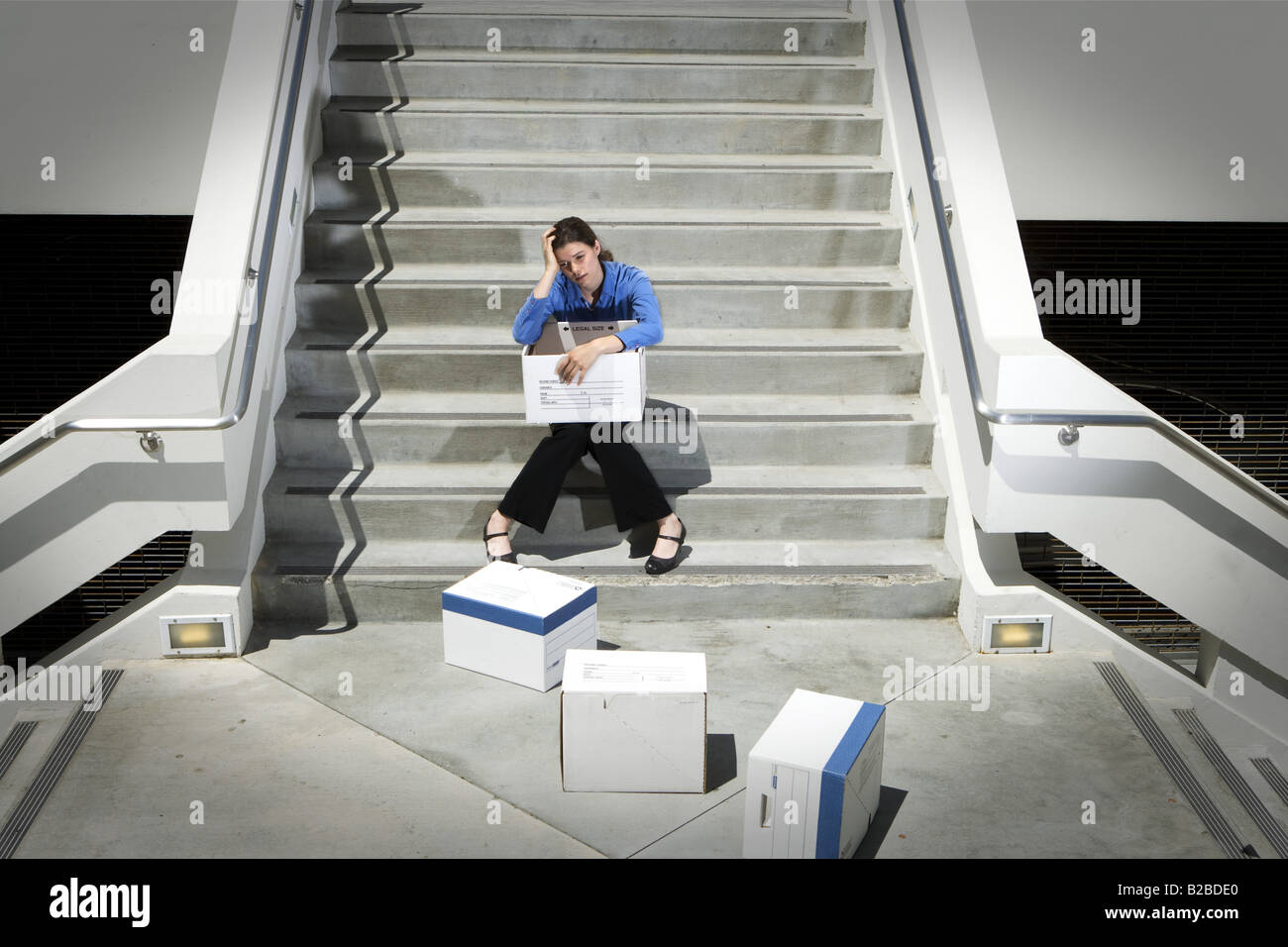 Businesswoman sitting on steps by dropped boxes of paperwork Stock ...