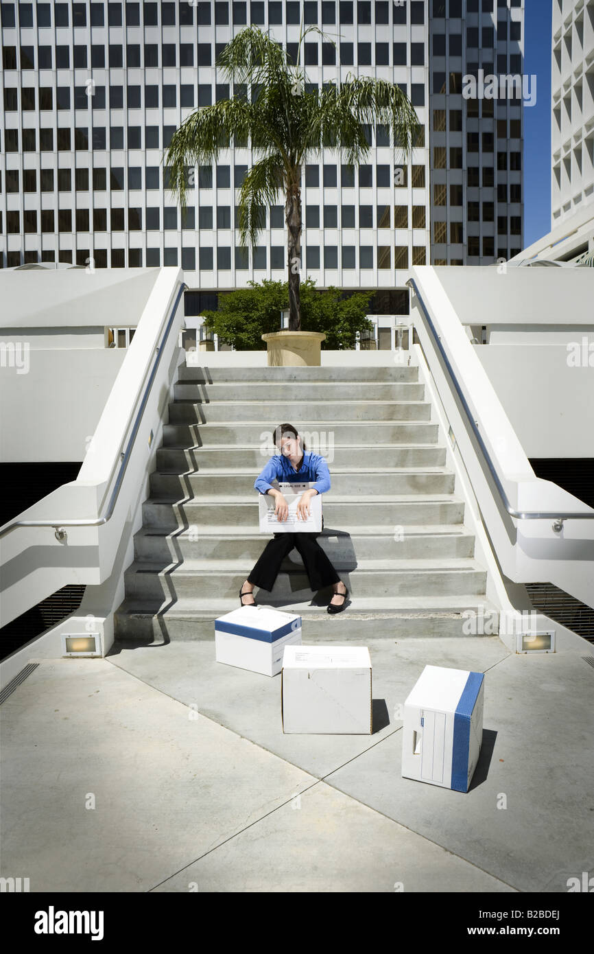 Businesswoman sitting on steps by dropped boxes of paperwork Stock ...