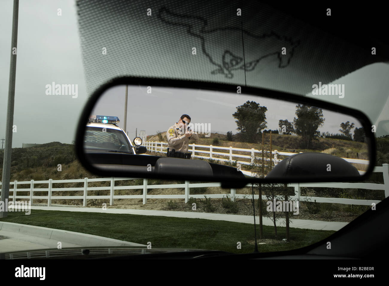 Police officer seen through rear view mirror Stock Photo - Alamy