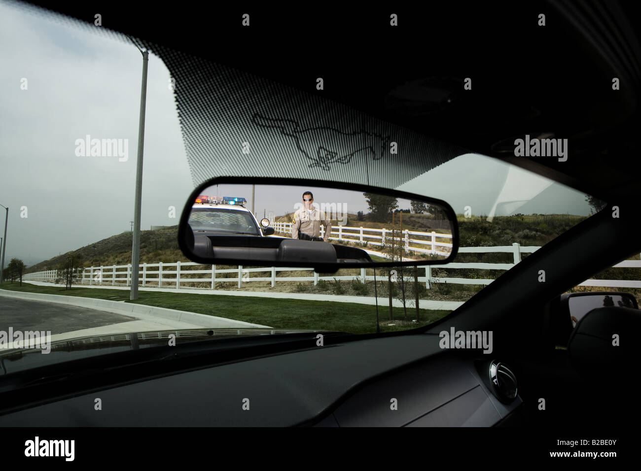 Police officer seen through rear view mirror Stock Photo - Alamy