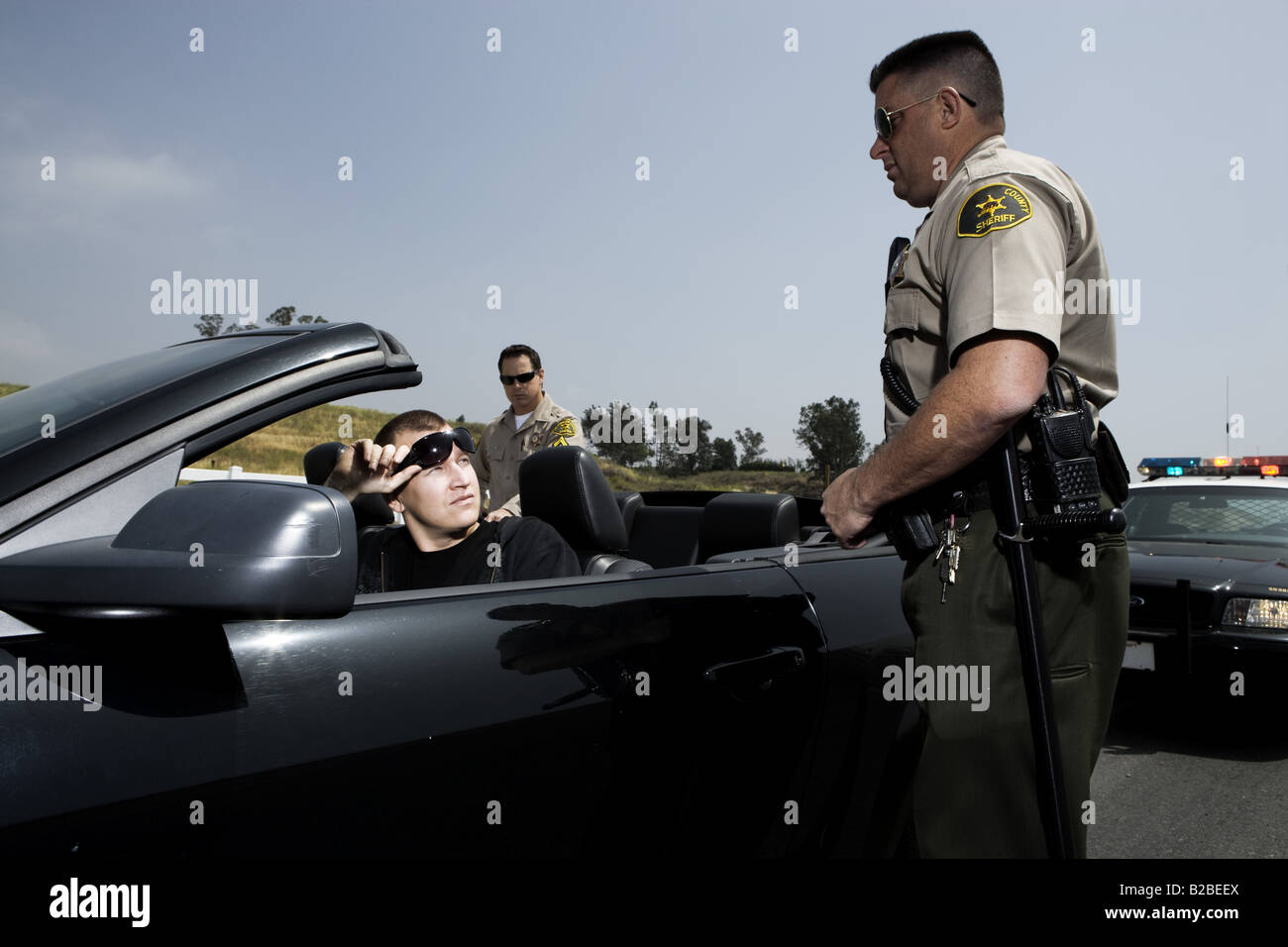 Two police officers apprehend man in black Mustang Stock Photo - Alamy