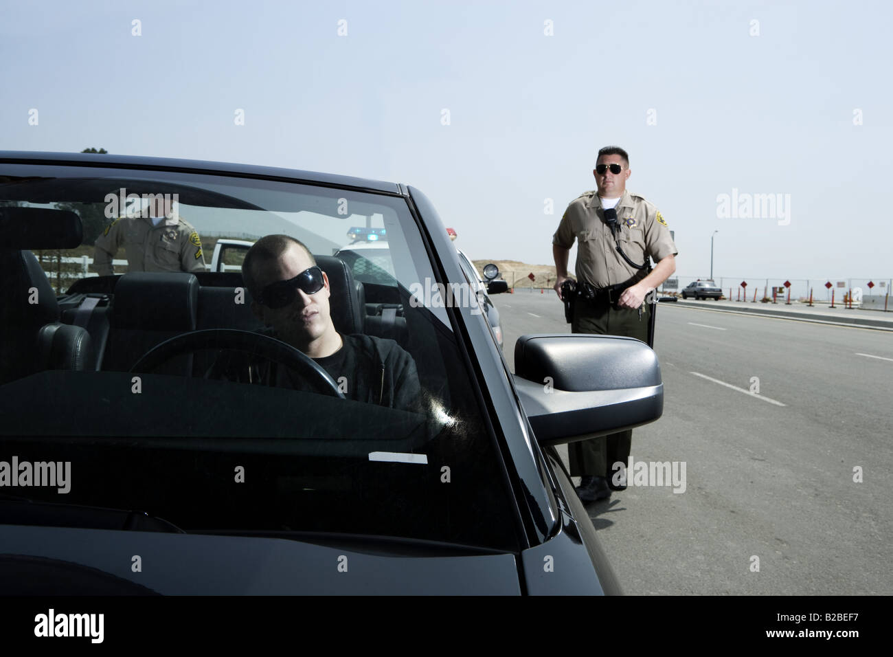Two police officers approaching man in black Mustang Stock Photo - Alamy