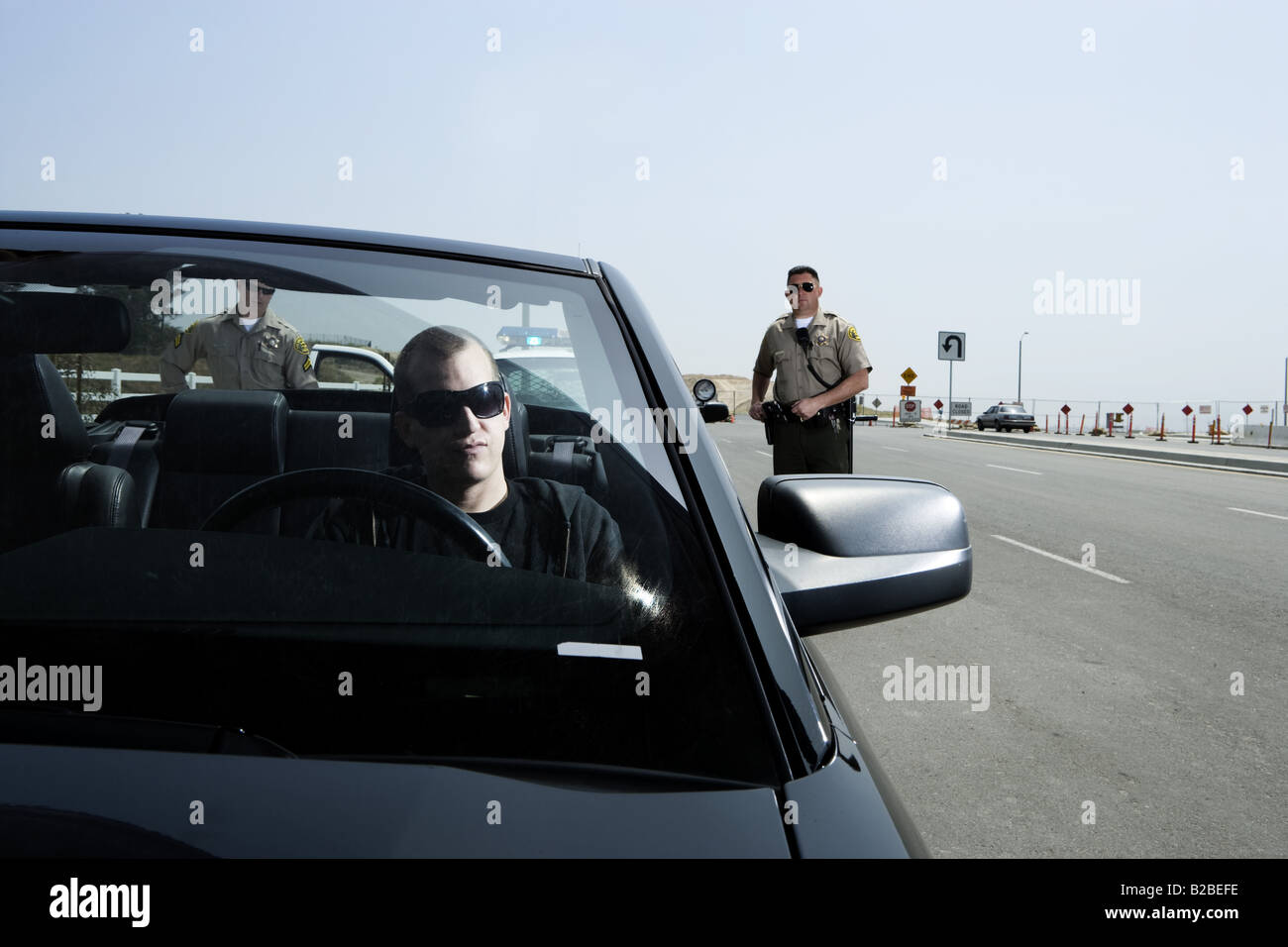 Two police officers approaching man in black Mustang Stock Photo - Alamy