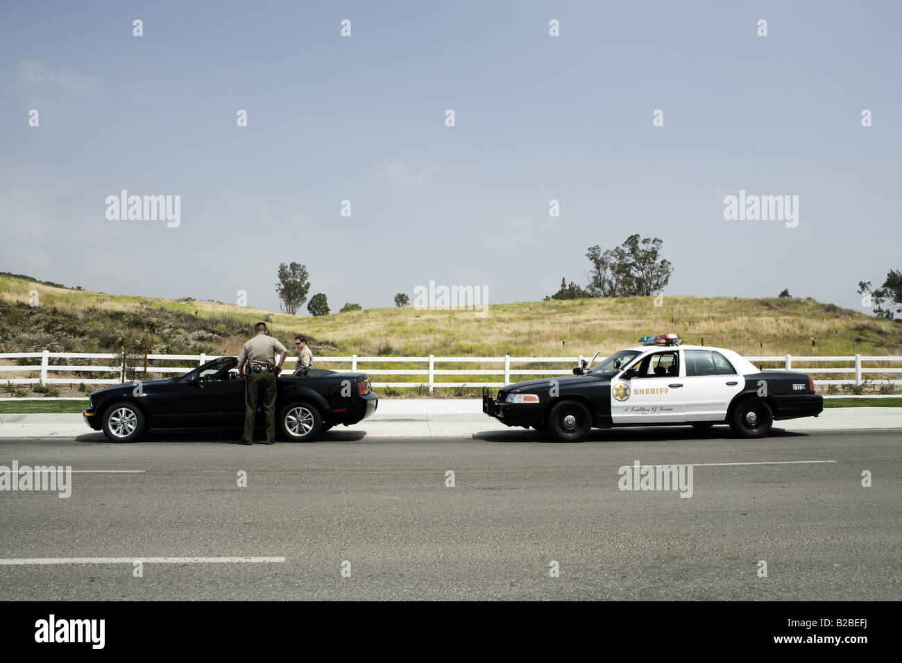 Two police officers approach man in Mustang Stock Photo - Alamy