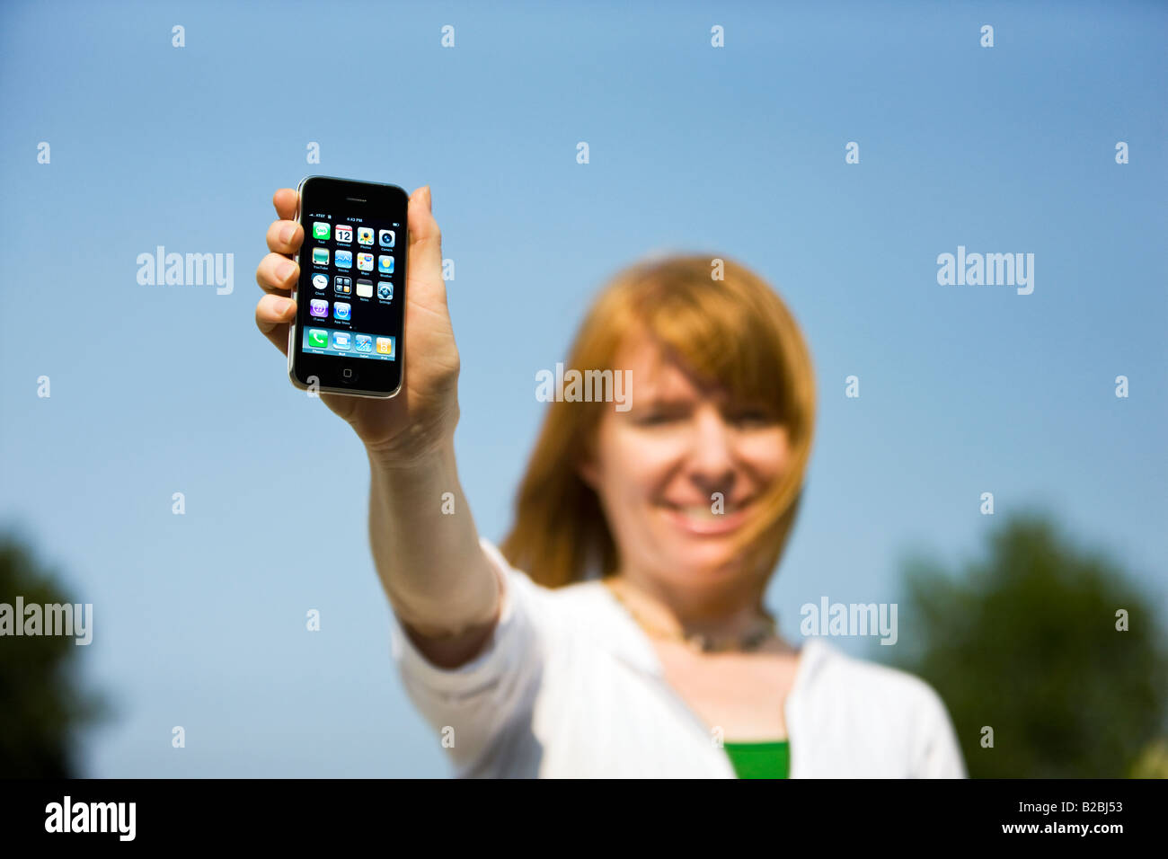 A woman shows off her Apple 3G iPhone by raising it up in her hand ...