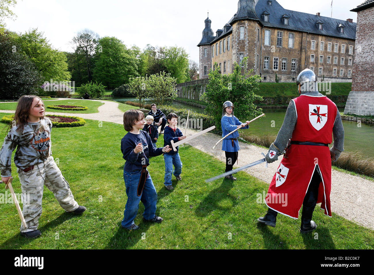 Children playing knights, sword fighting against a man dressed in a ...
