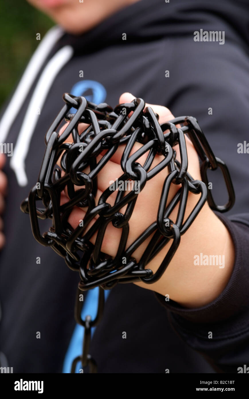 Metal chain wrapped around boys fist Stock Photo - Alamy