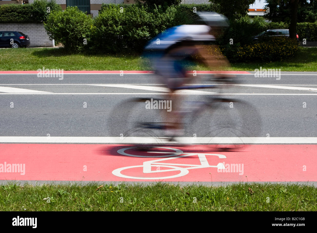 Cyclist riding quickly along a red bike lane with a bike lane street ...