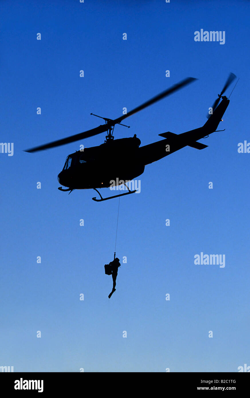 Combat swimmer hanging from a rope under a Bell UH-1D model helicopter ...