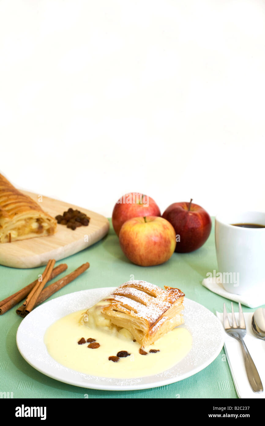 Apple strudel with custard, a cup of coffee, apples, cinnamon sticks ...