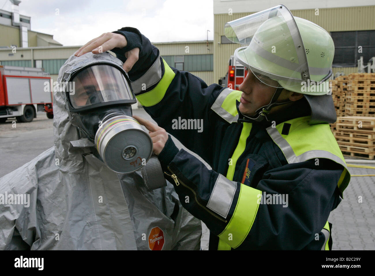 Fireman helping a colleague put on a protective overall during a ...
