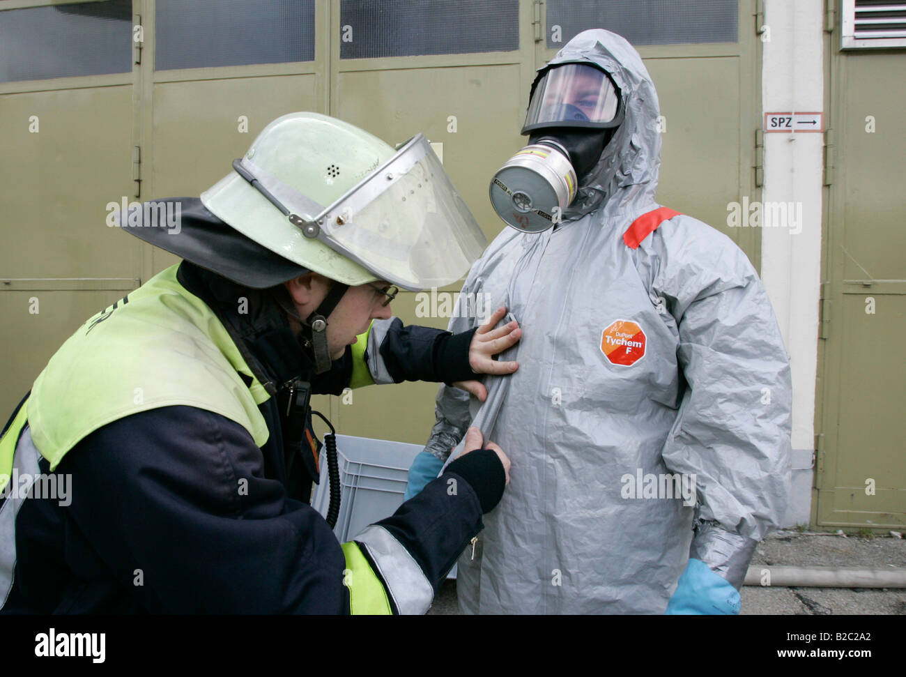 Fireman helping a colleague put on a protective overall during a ...