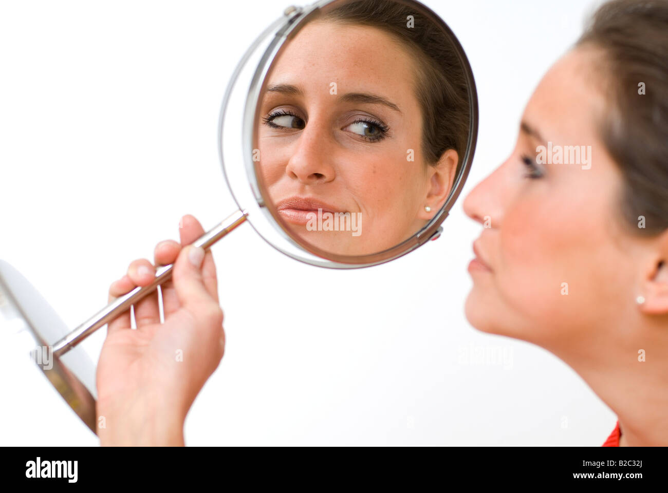 Young woman looking at a hand mirror Stock Photo - Alamy