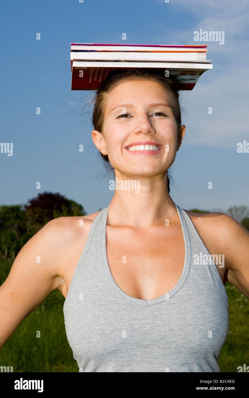 young woman staying straightly with books on her head Stock Photo - Alamy