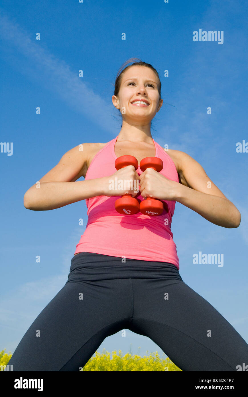 young woman lifting barbells outdoor, knee bend Stock Photo - Alamy