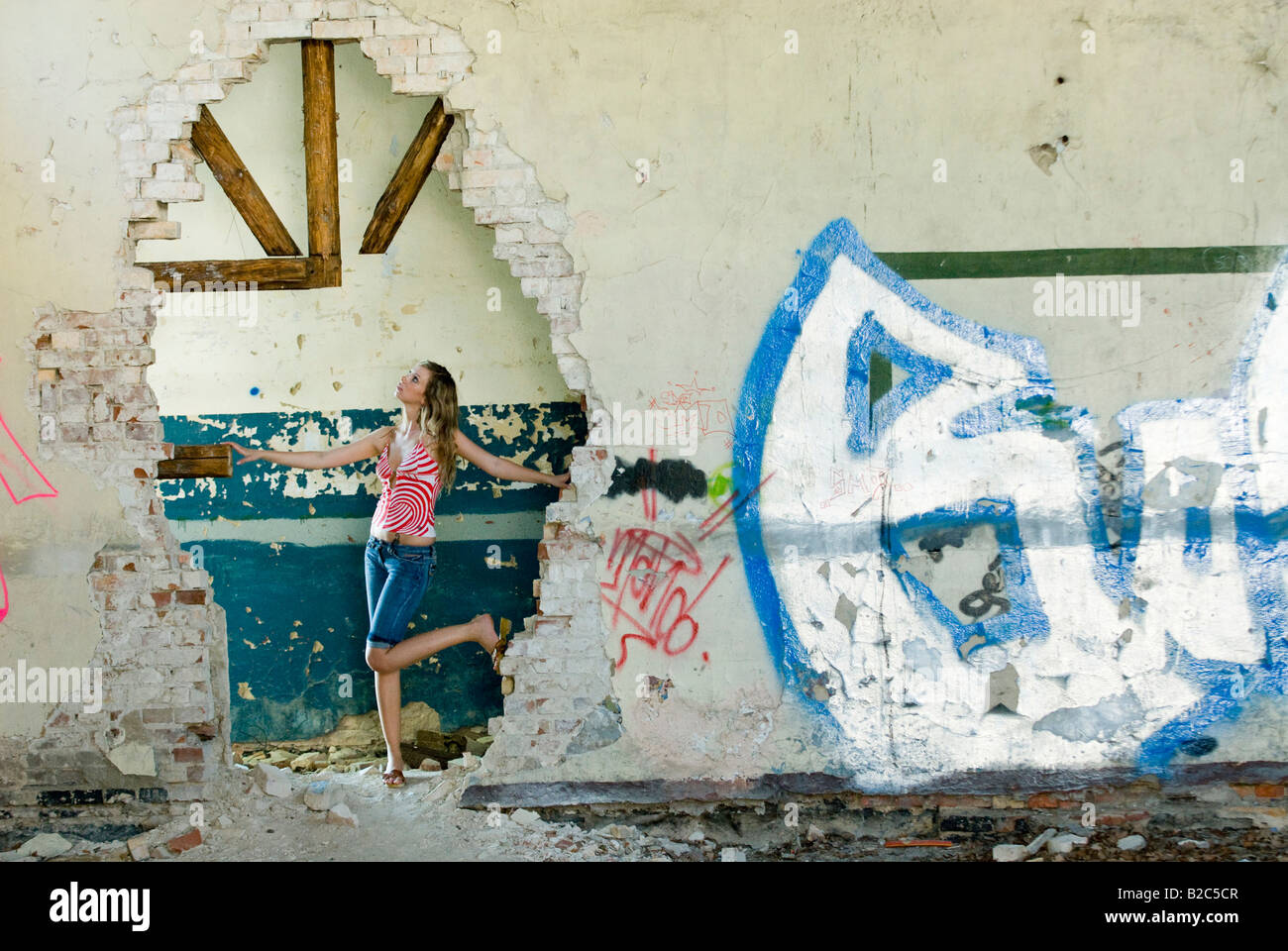 young woman posing in a walls hole in a knock down building Stock Photo ...