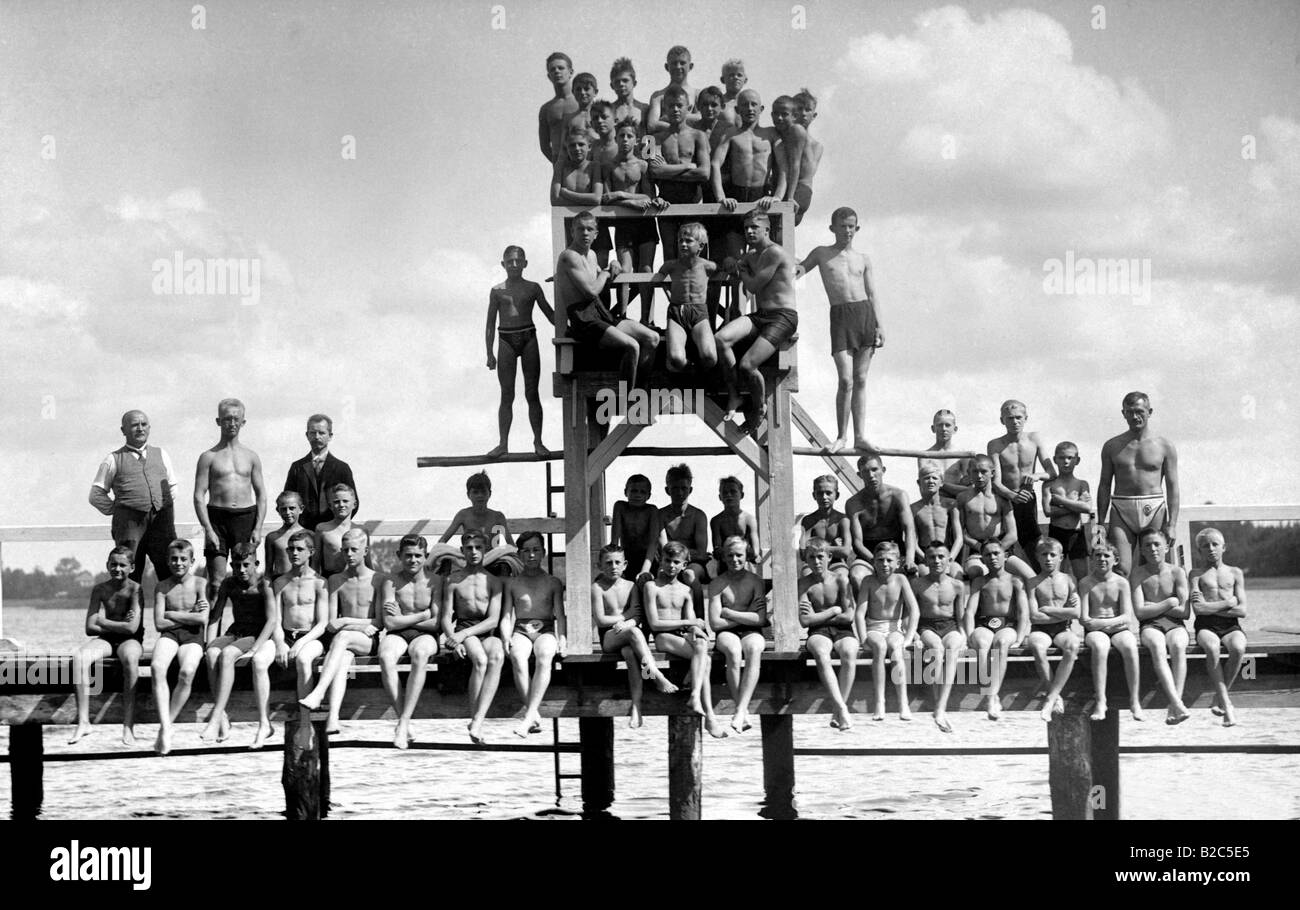 Adolescent swimmers posing in trunks on a diving platform, historic ...