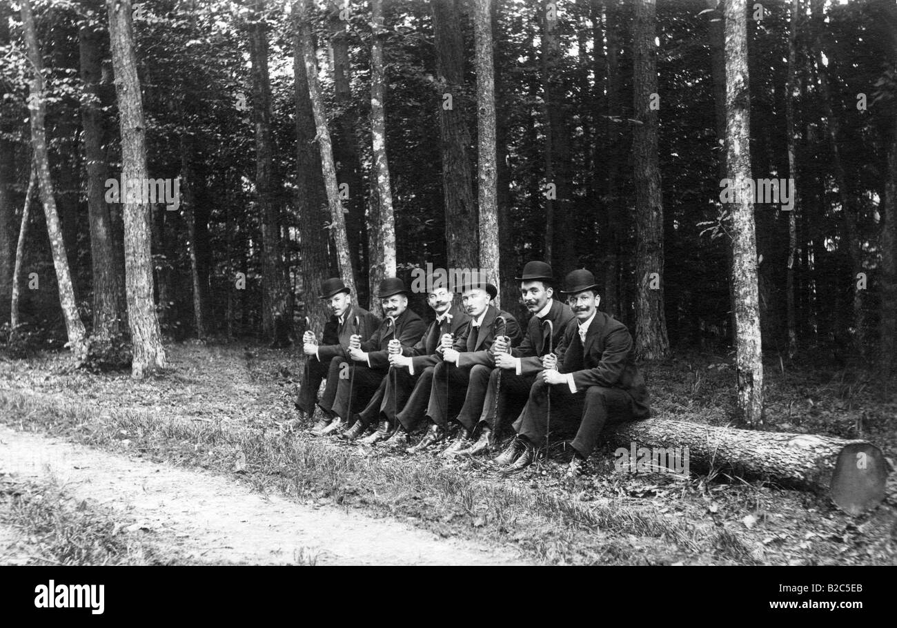 Group of men sitting on a tree trunk, historic picture from about 1930 ...