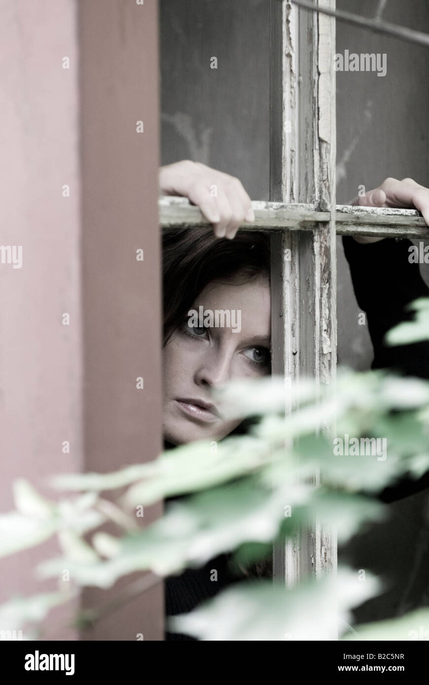 young woman looking out of a window longingly Stock Photo - Alamy
