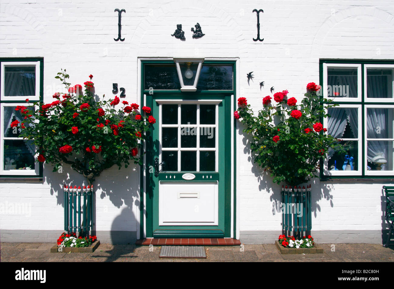 Red roses in front of entrance, historic house with a decorative wooden ...