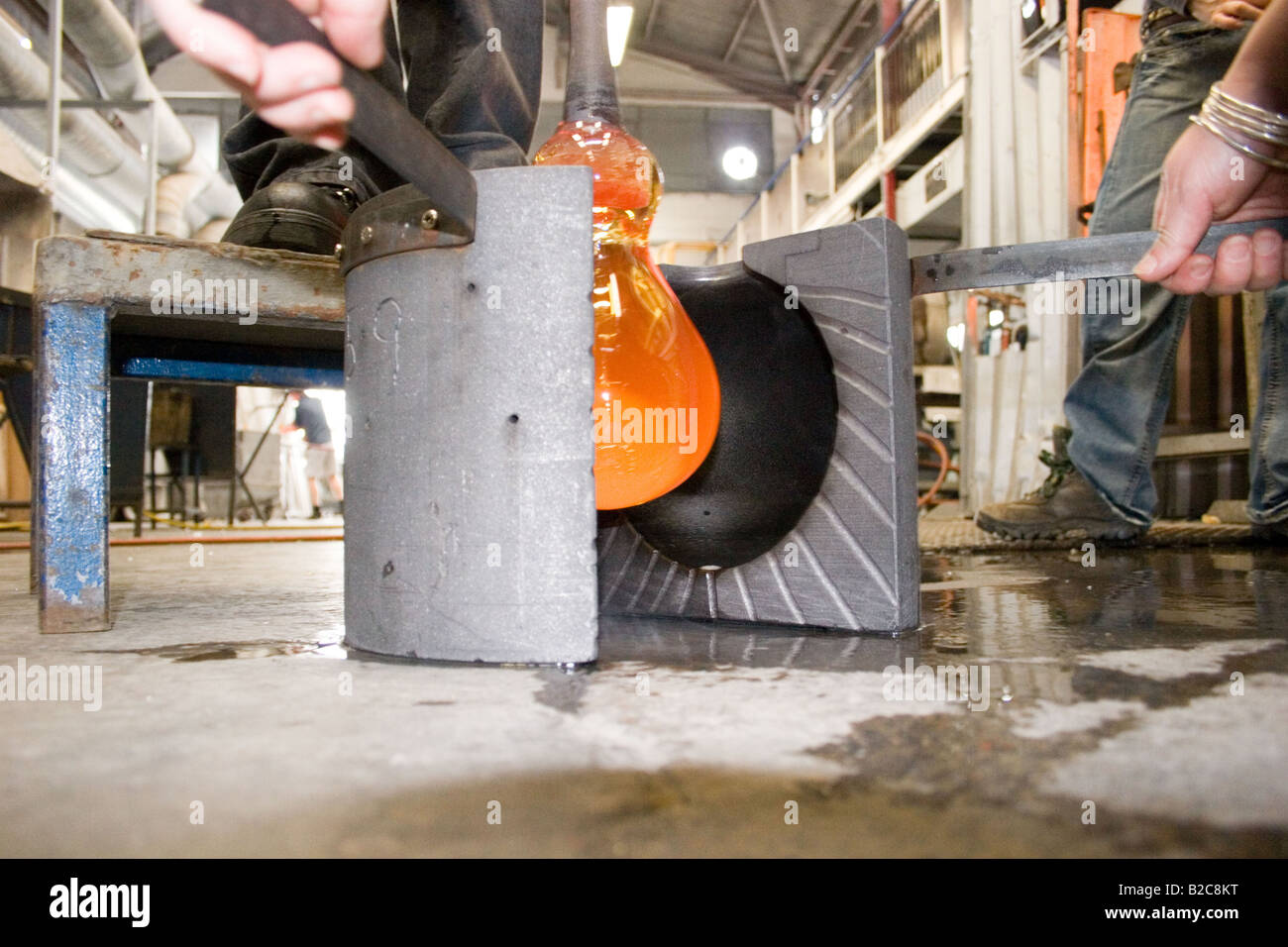 Molten glass being blown in mould through rod by craftman. 60875 ...