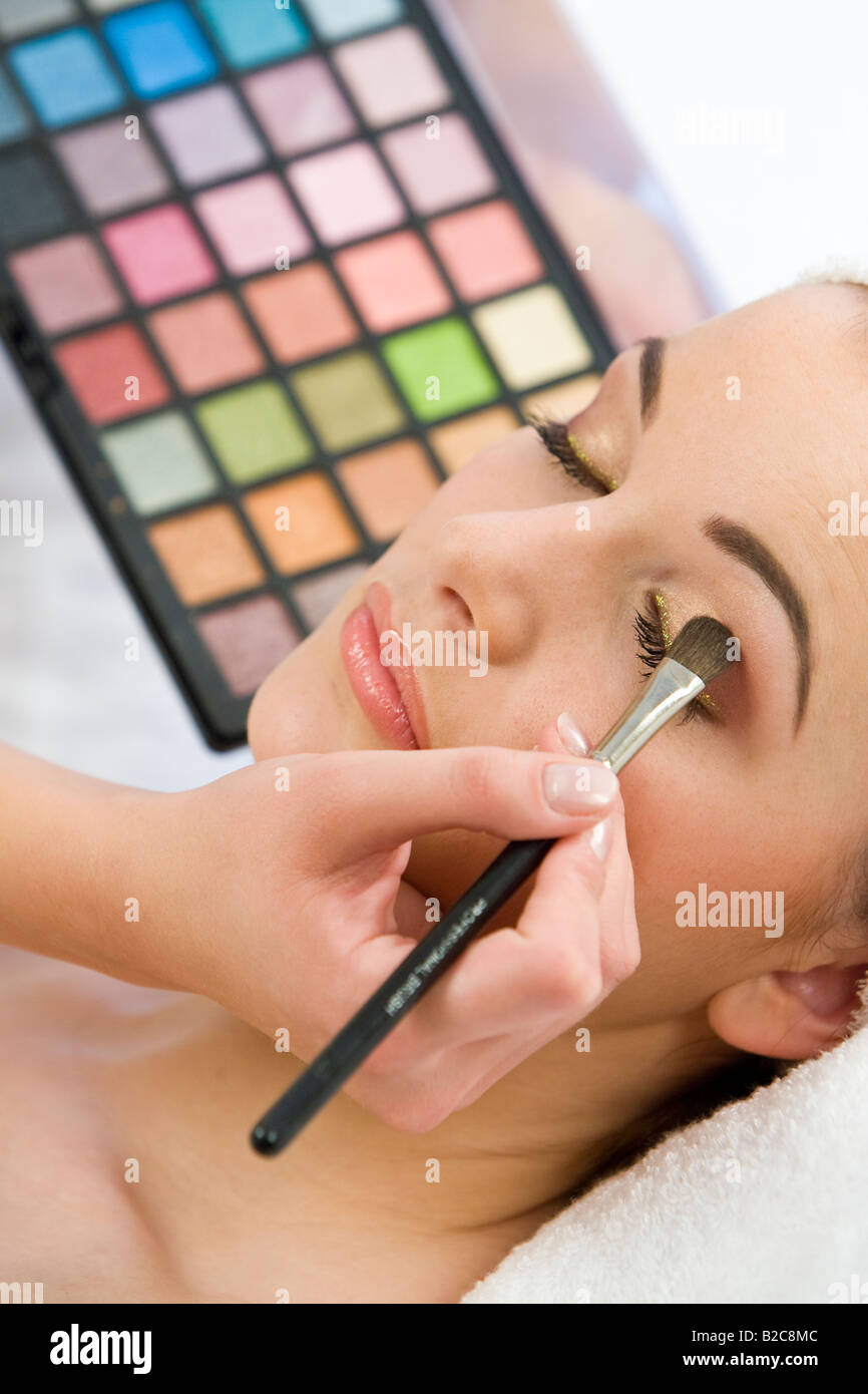 A beautiful young woman having the final touches applied to her make up ...
