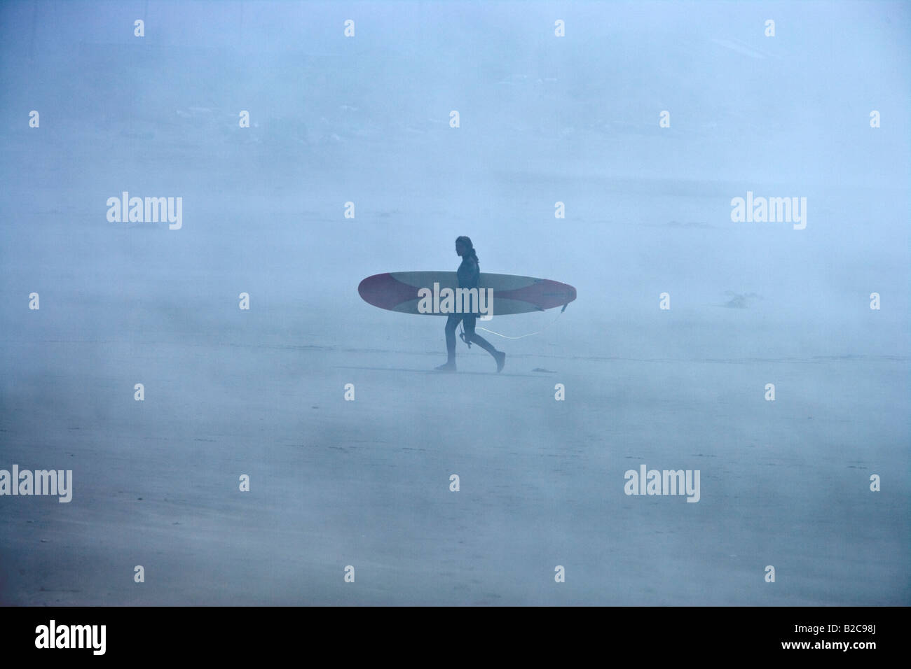 Female surf boarder walking on foggy beach Stock Photo - Alamy