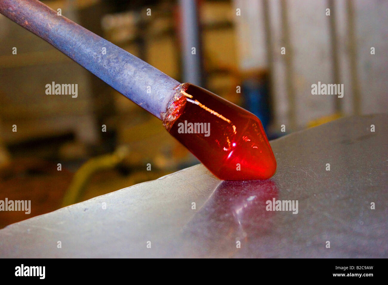 Glass works. End of rod with molten glass used by glass blower worker ...