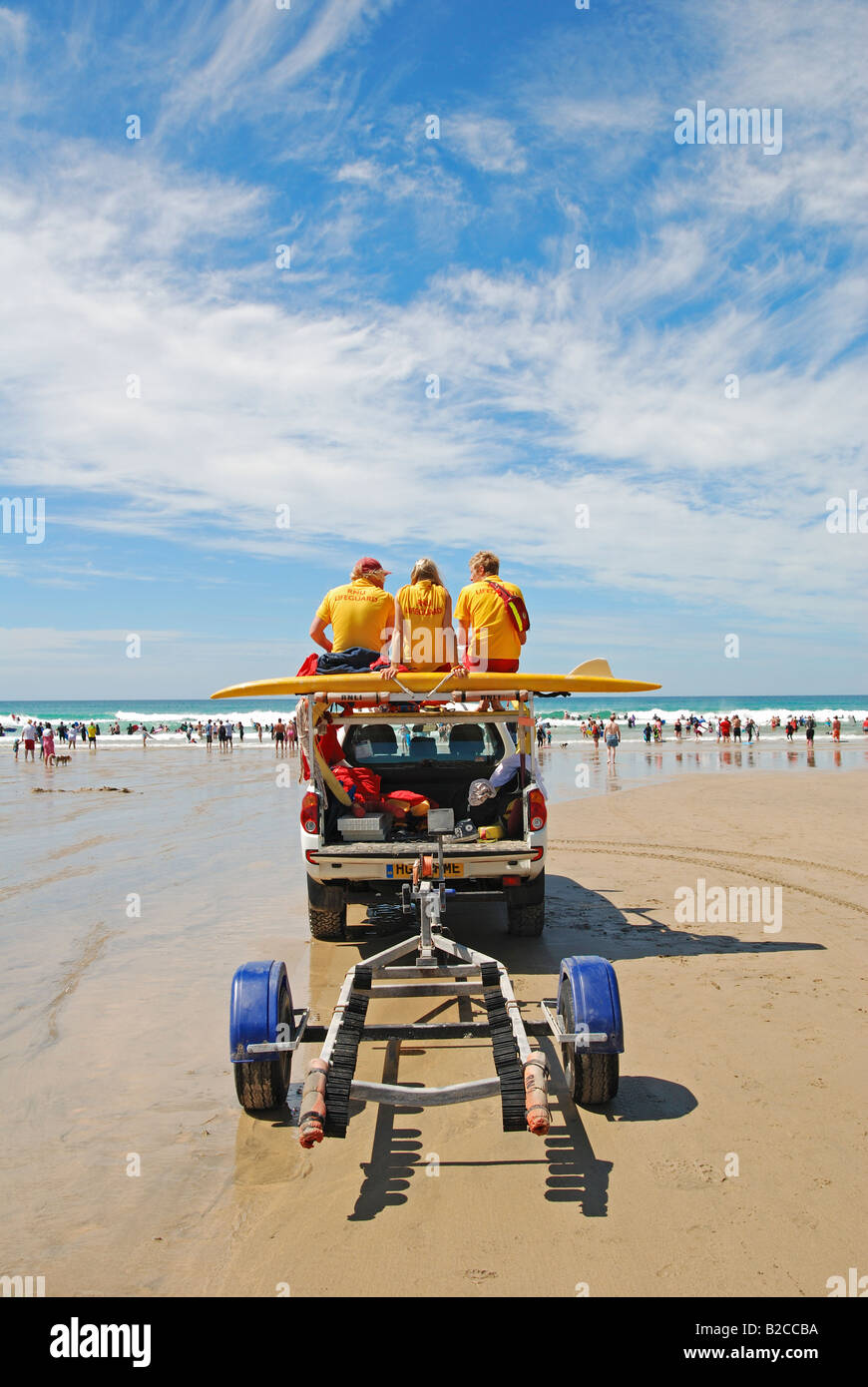 three lifeguard sitting on top of their rescue vehicle watching people ...
