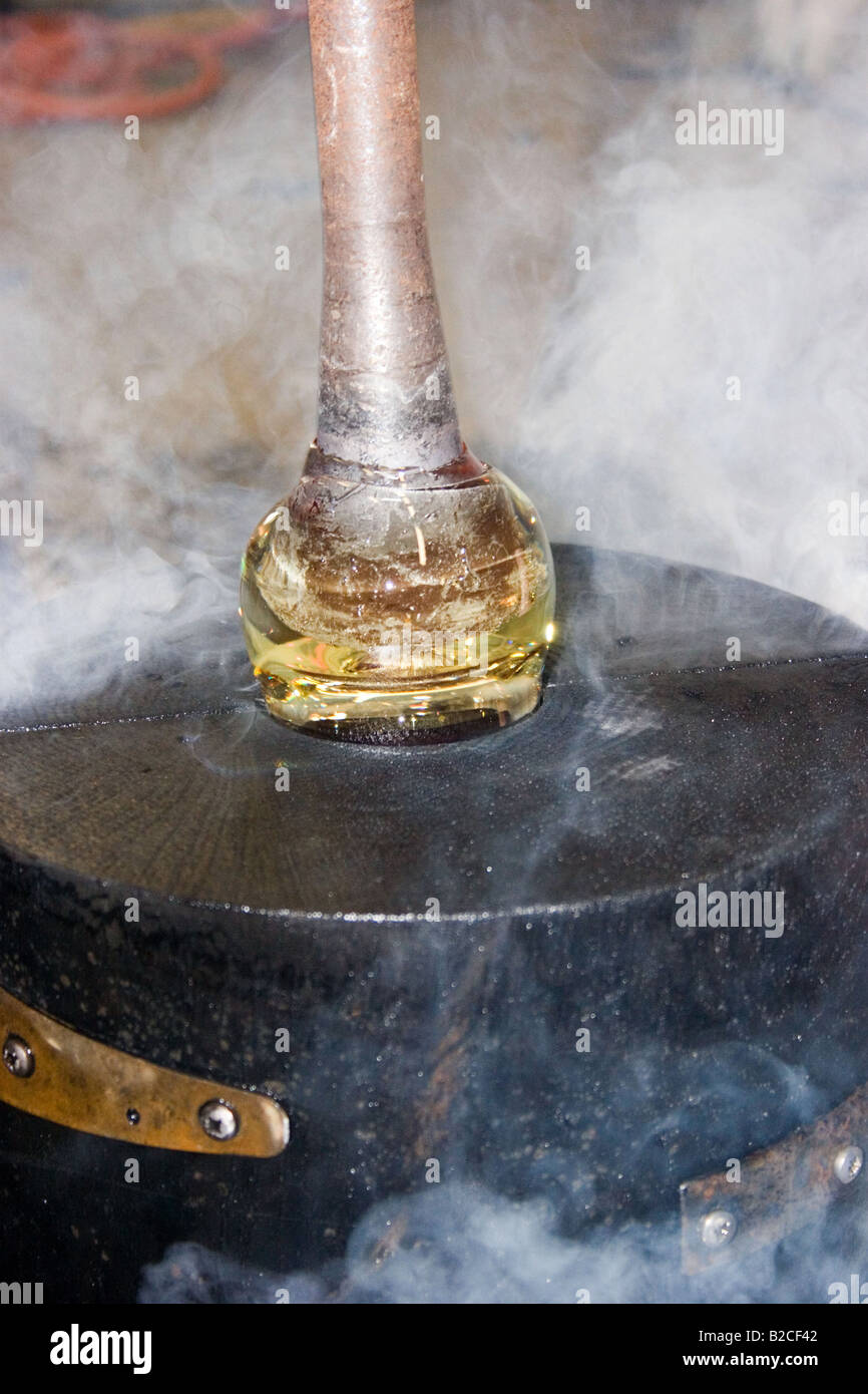 Molten glass being blown in mould through rod by craftman. 60650 ...