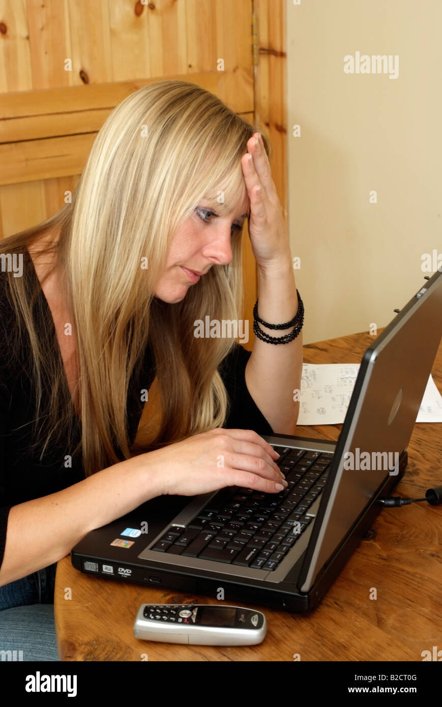 Woman using laptop computer with hand on forehead Stock Photo - Alamy