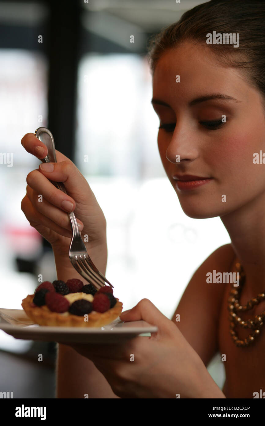 Young woman eating dessert in café Stock Photo - Alamy