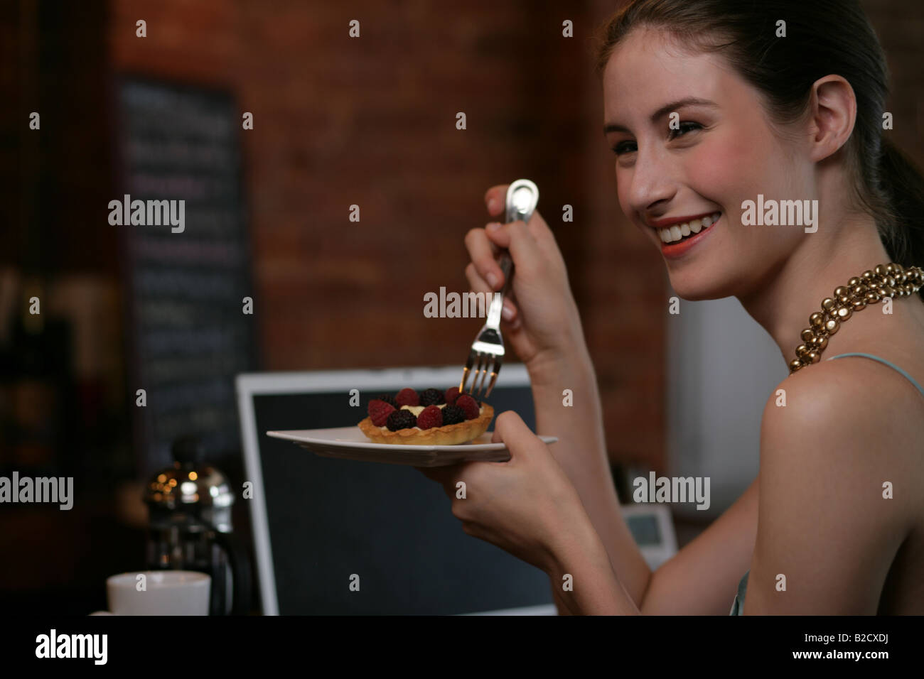 Happy young woman eating dessert in café Stock Photo - Alamy