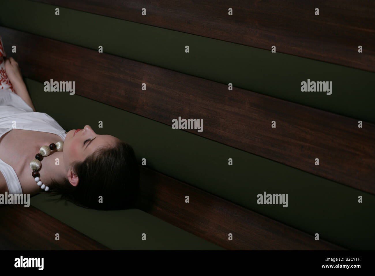 Young woman laying on café bench Stock Photo - Alamy