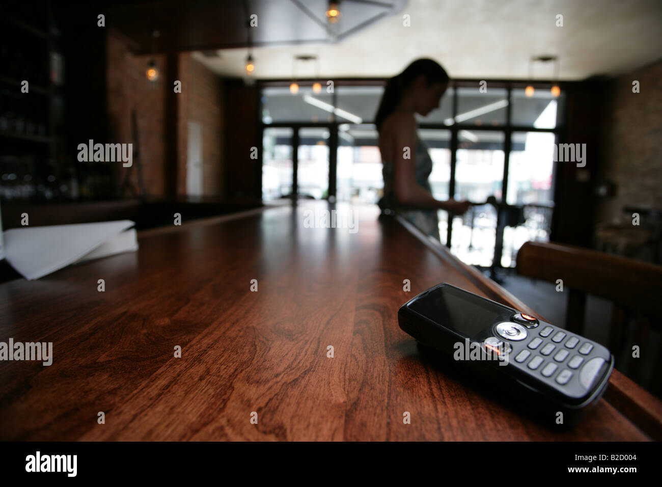Cell phone on bar with woman standing in background Stock Photo - Alamy