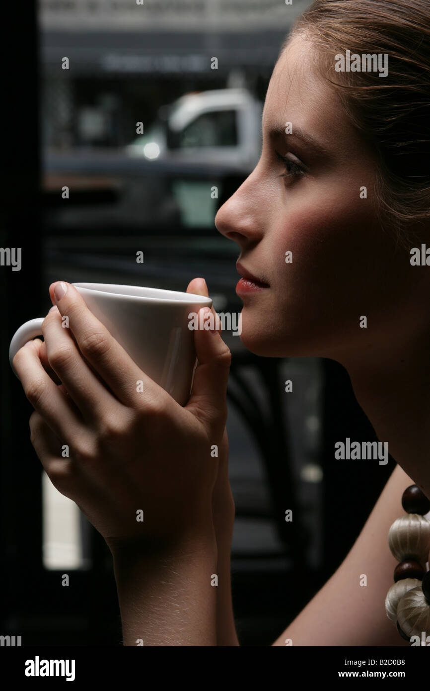 Young woman drinking coffee in café Stock Photo - Alamy